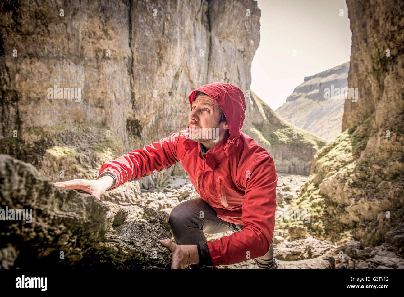A mountaineer climbing over rocks in rugged terrain Stock Photo - Alamy