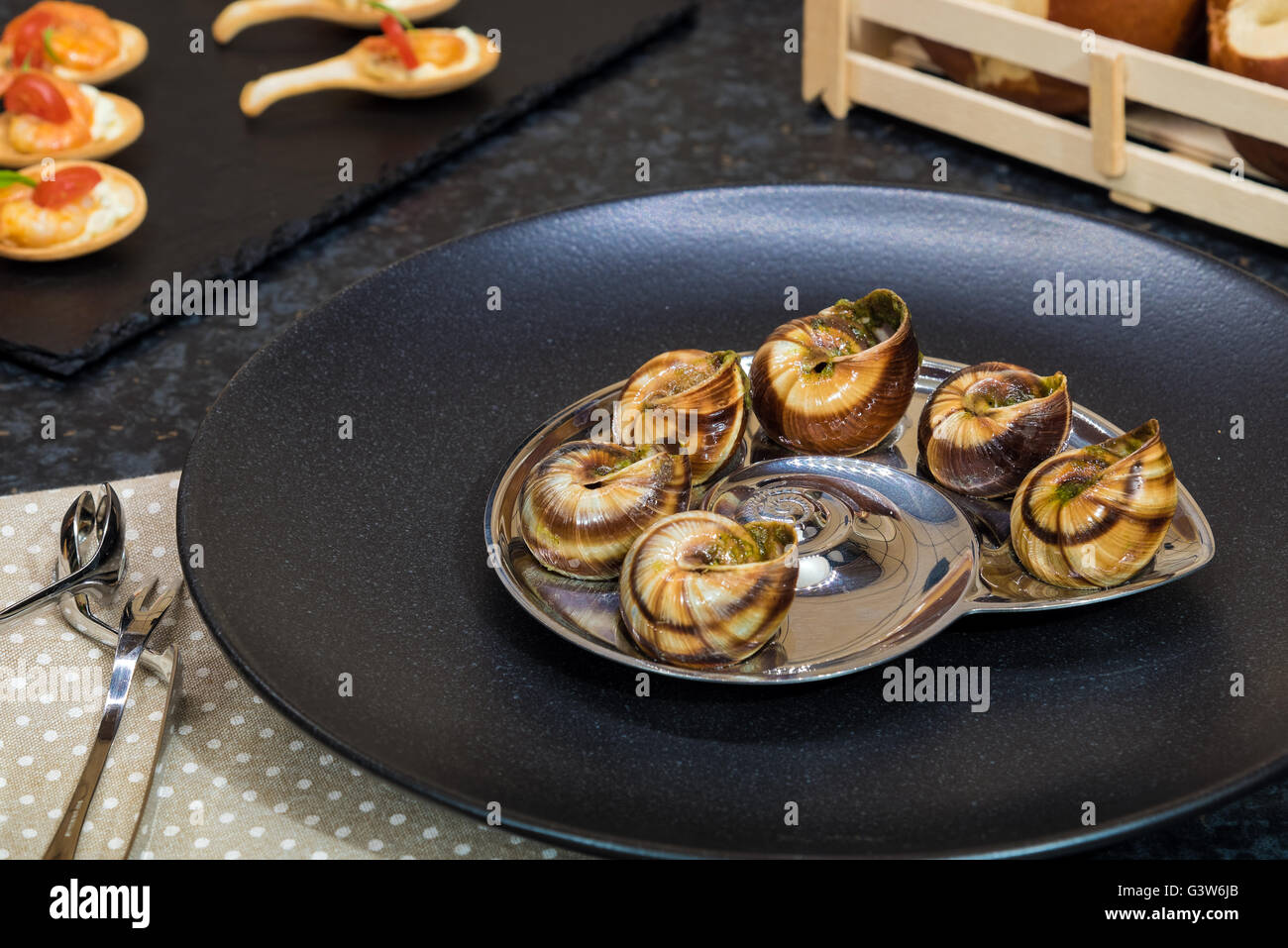 Prepared snails with garlic and parsley in black plate Stock Photo - Alamy