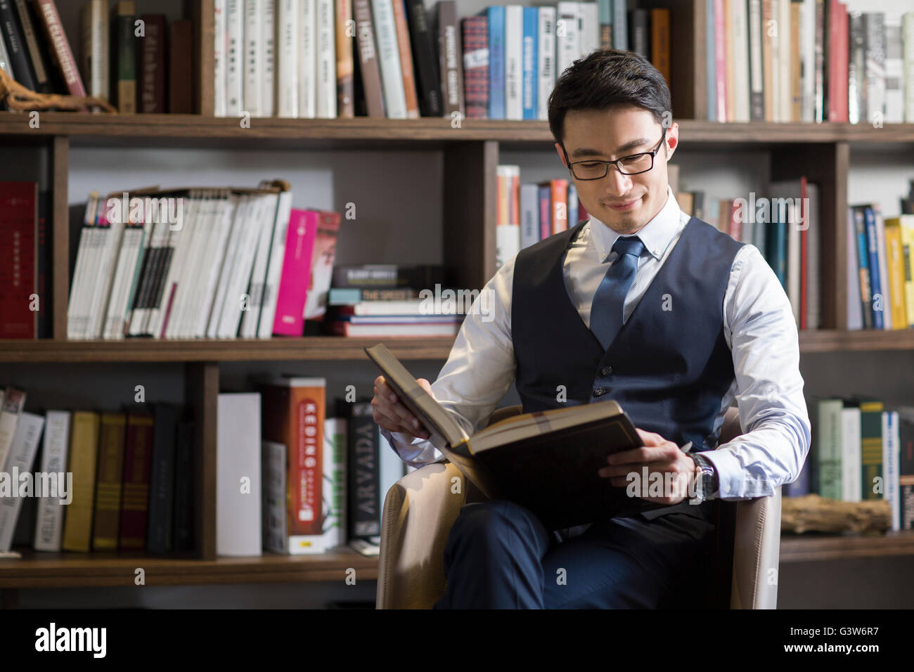 Young businessman reading book in his study Stock Photo - Alamy
