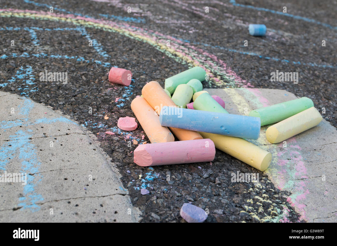Close up of a pile of chunky coloured chalk on a road with drawings on ...