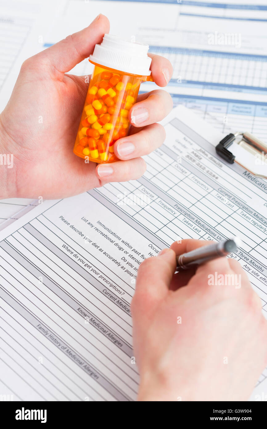 Doctor holding pill bottle and filling documents Stock Photo - Alamy
