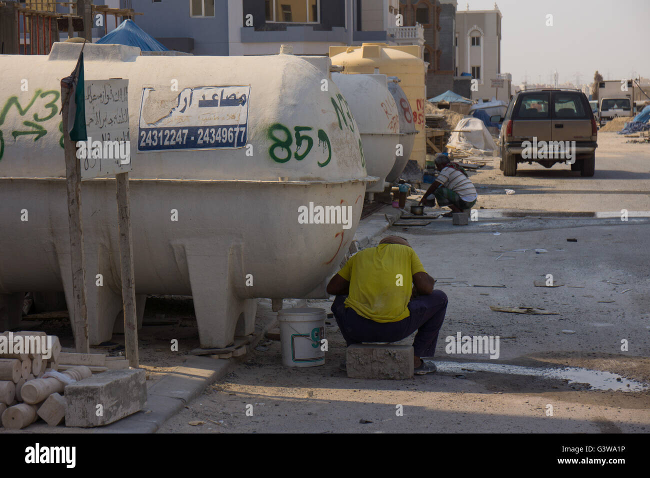 Builders on a construction site washing at water tanks in the early ...