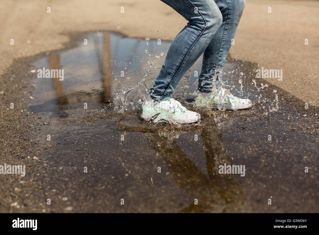 Woman in gumshoes jumping in a puddle. Close up shot of foots in a ...