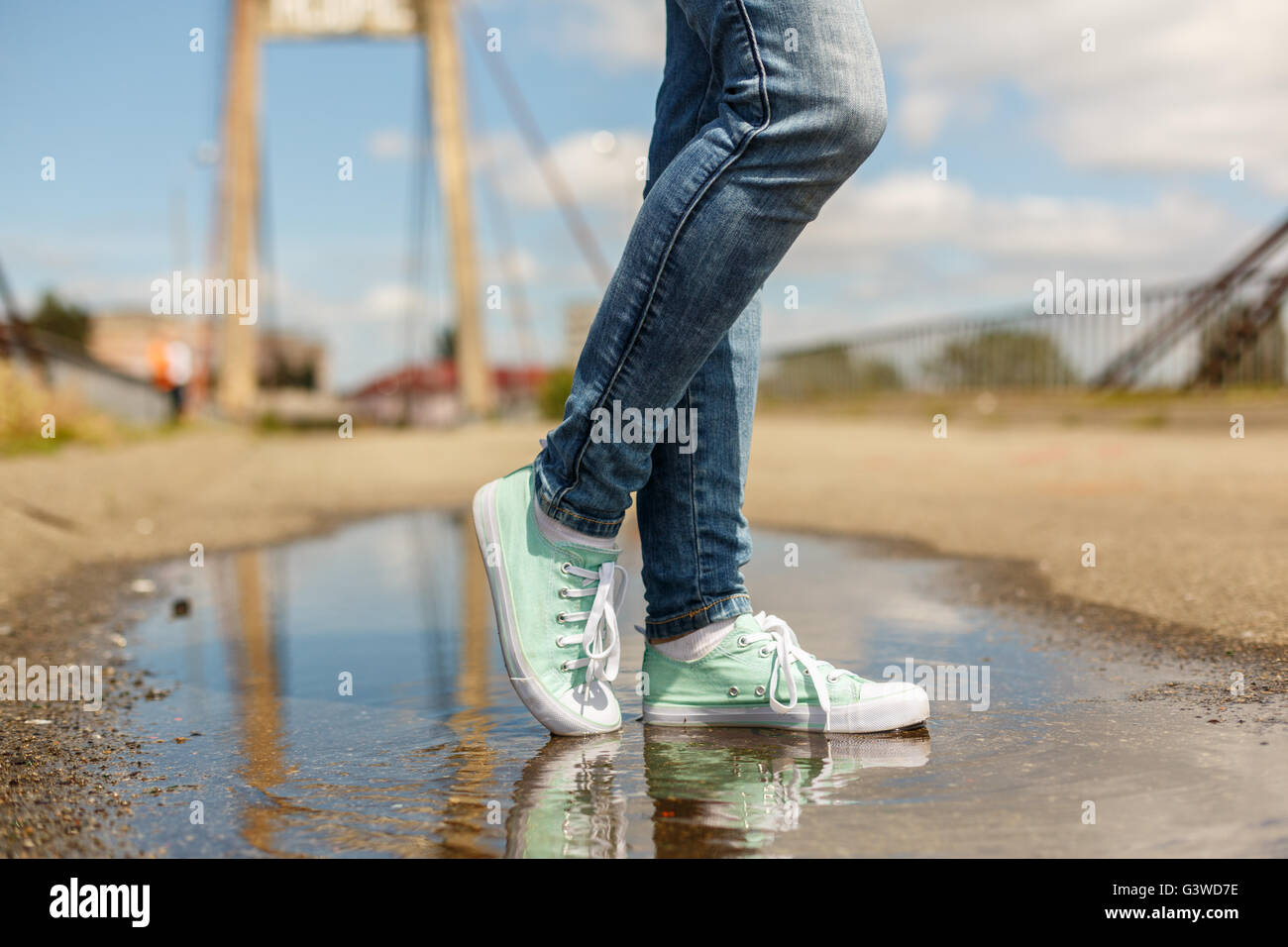 Woman in sport shoes standing in a puddle. Close up shot of foots in a ...