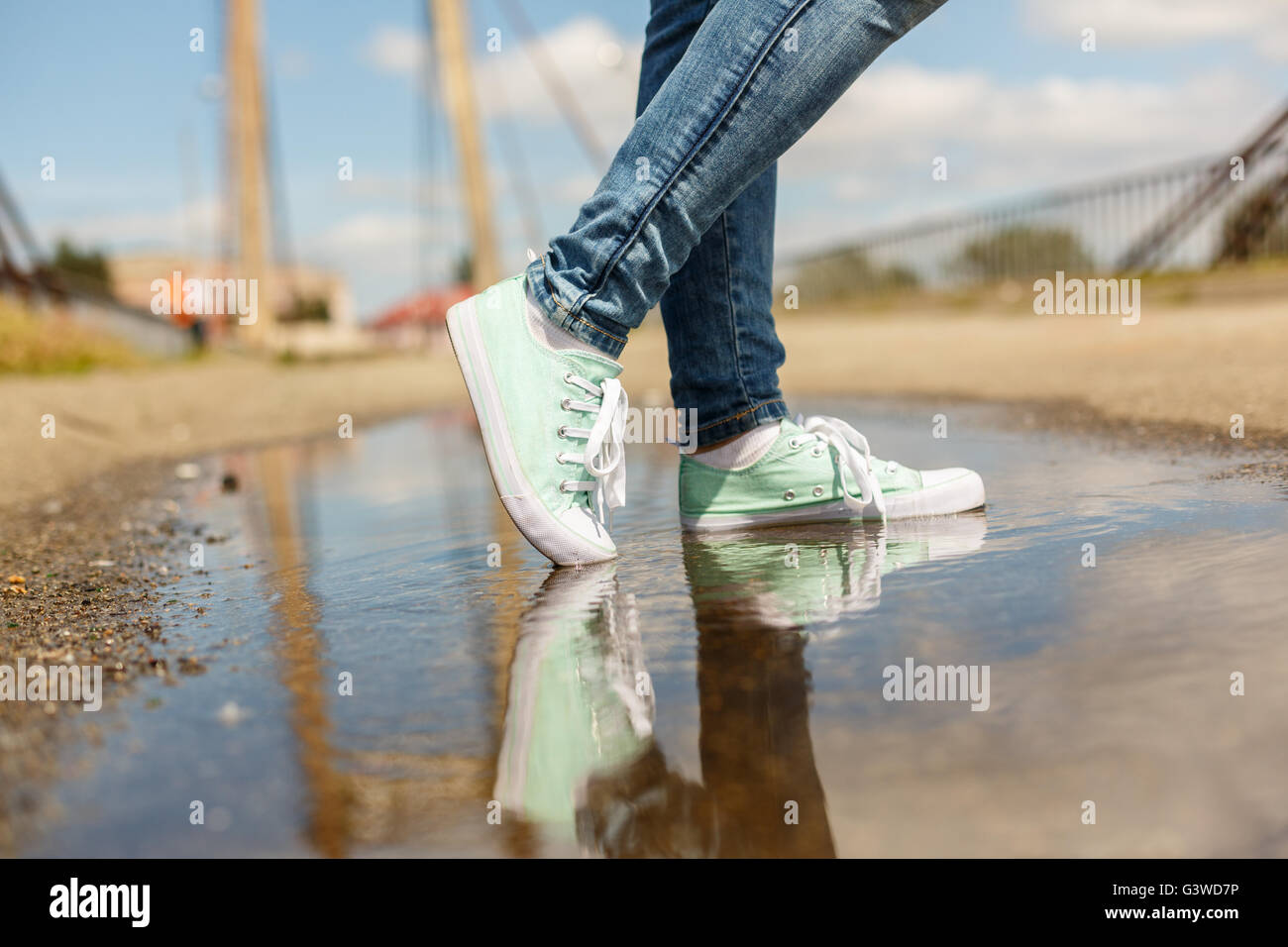 Woman in sport shoes standing in a puddle. Close up shot of foots in a ...