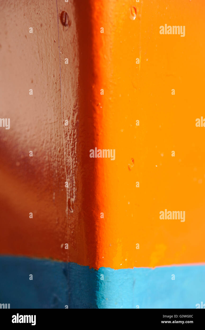 Hull of bright orange fishing boat with blue stripe Stock Photo - Alamy