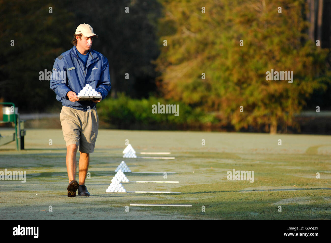 caddy setting up pyramids of golf balls on driving range in preparation ...