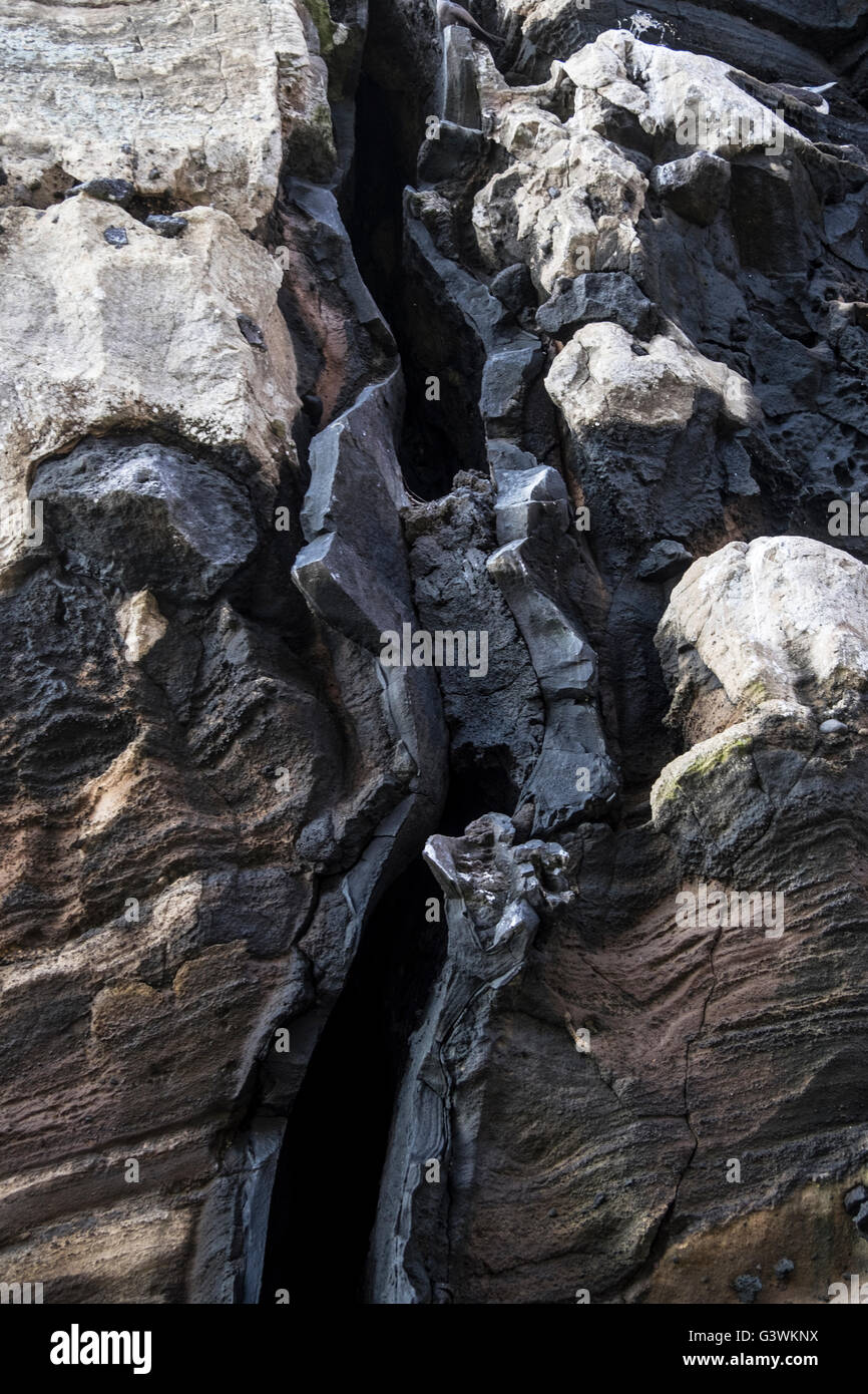 Volcanic activity has caused a vertical split in these rocks in a cliff ...