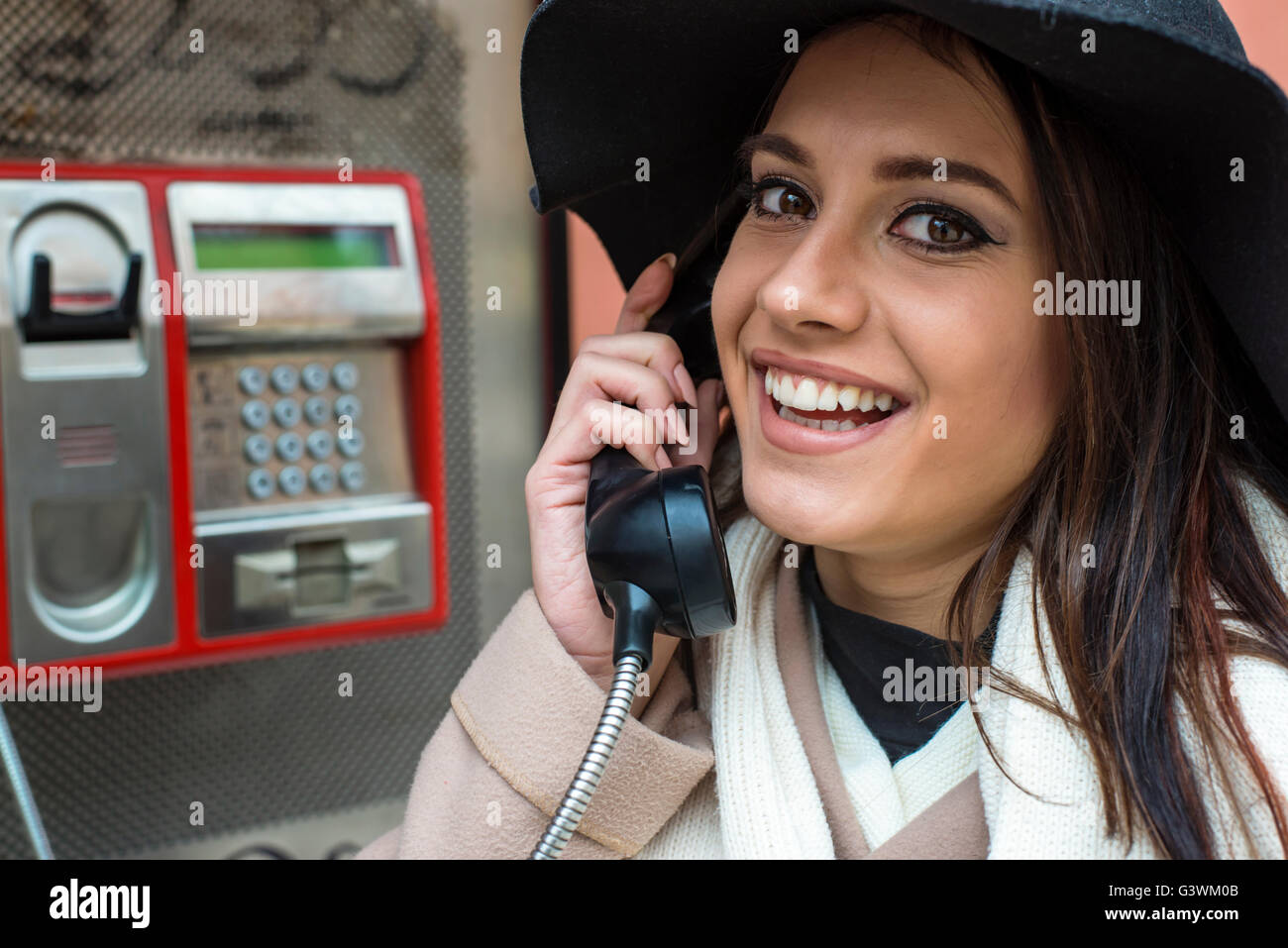 Pretty young woman having a call on the public phone Stock Photo - Alamy