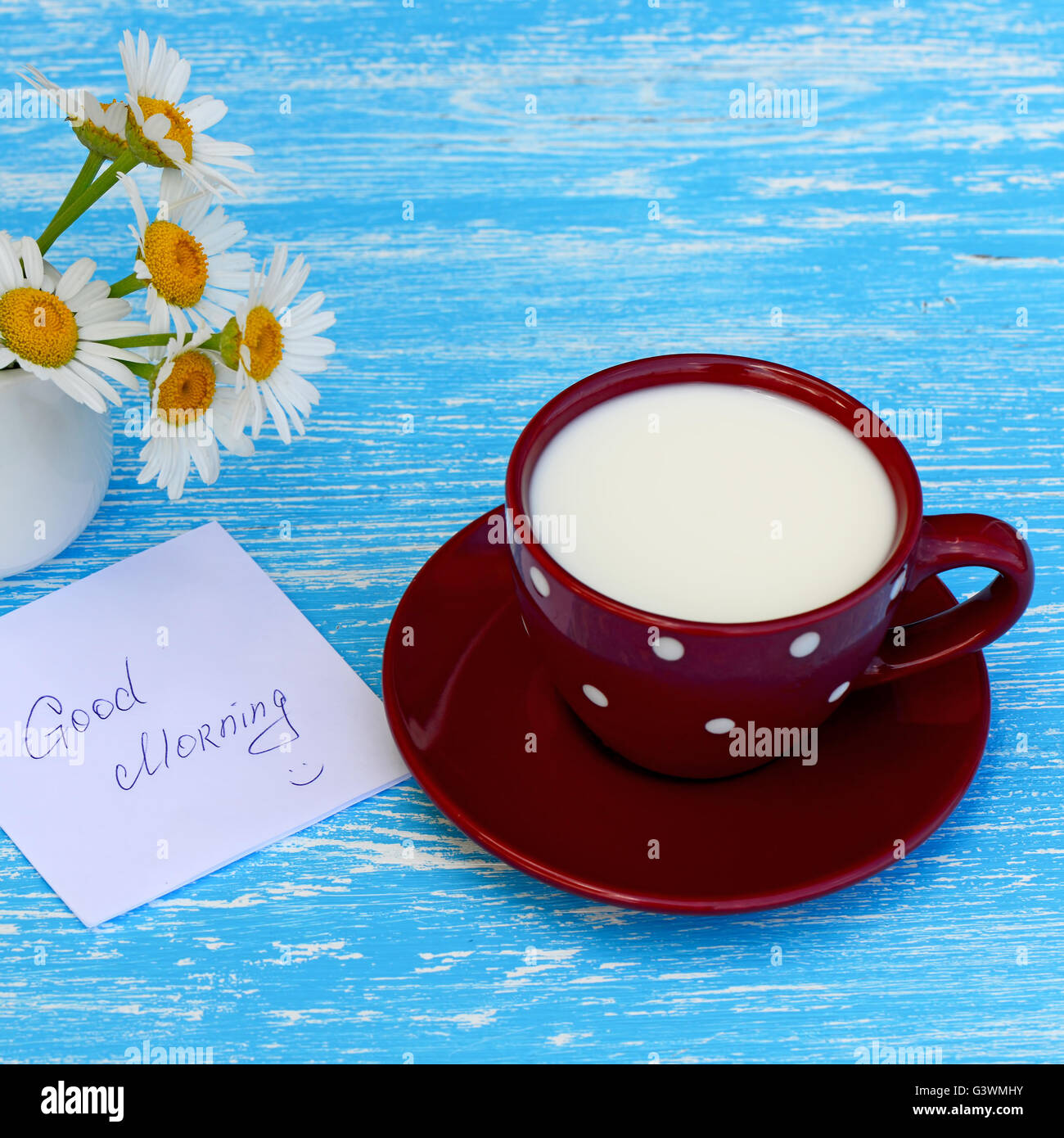Daisy flowers and cup of milk with good morning note on rustic blue ...
