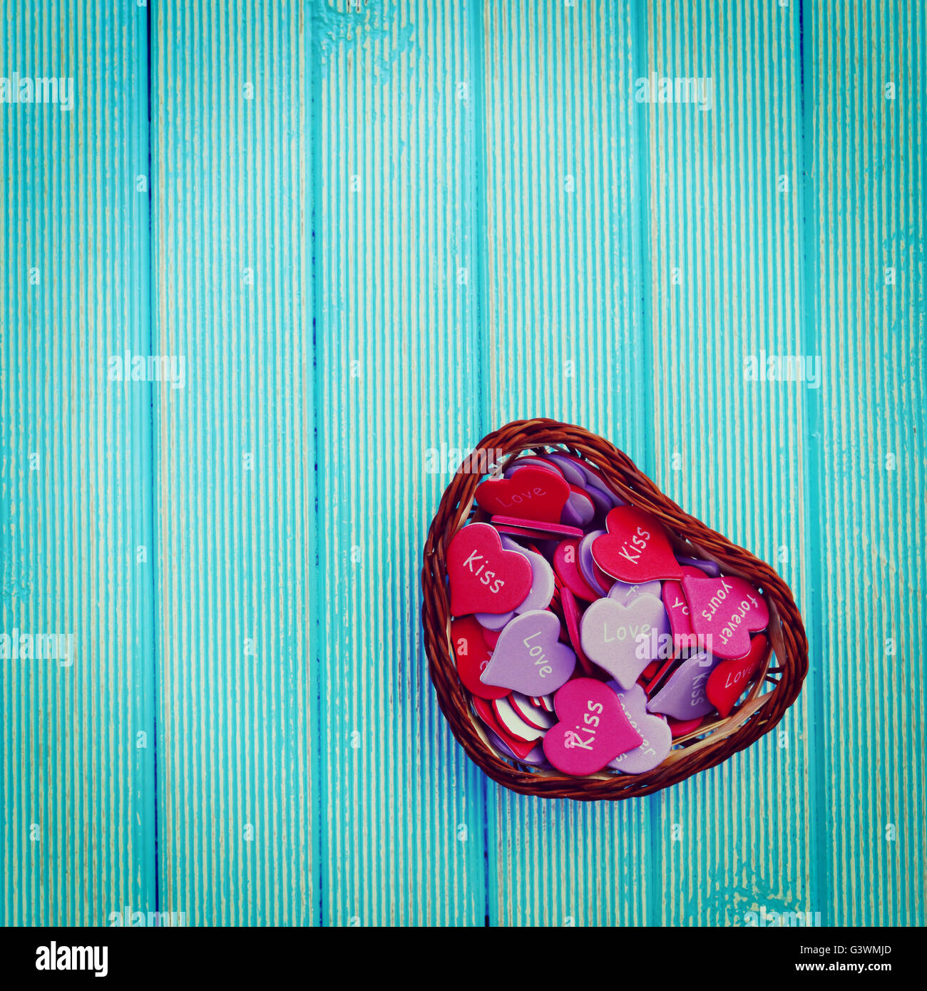 Full basket with hearts on a blue wooden background. Photo in vintage ...