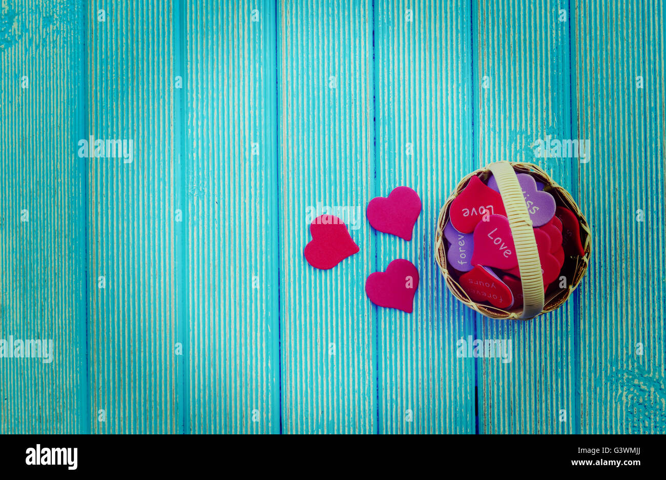 Full basket with hearts on a blue wooden background. Photo in vintage ...
