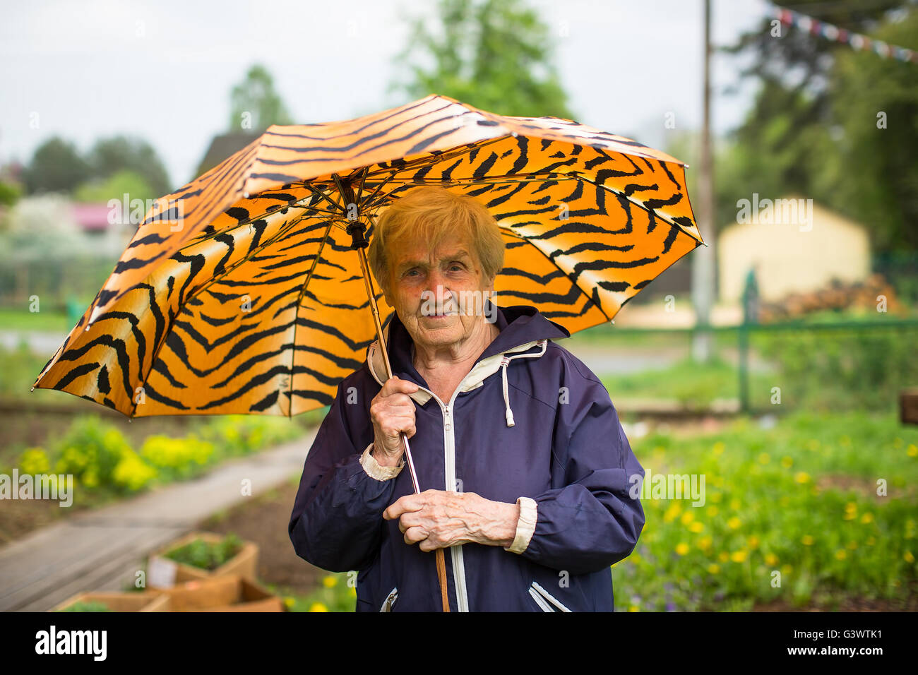 Elderly woman outdoors standing under a umbrella Stock Photo - Alamy