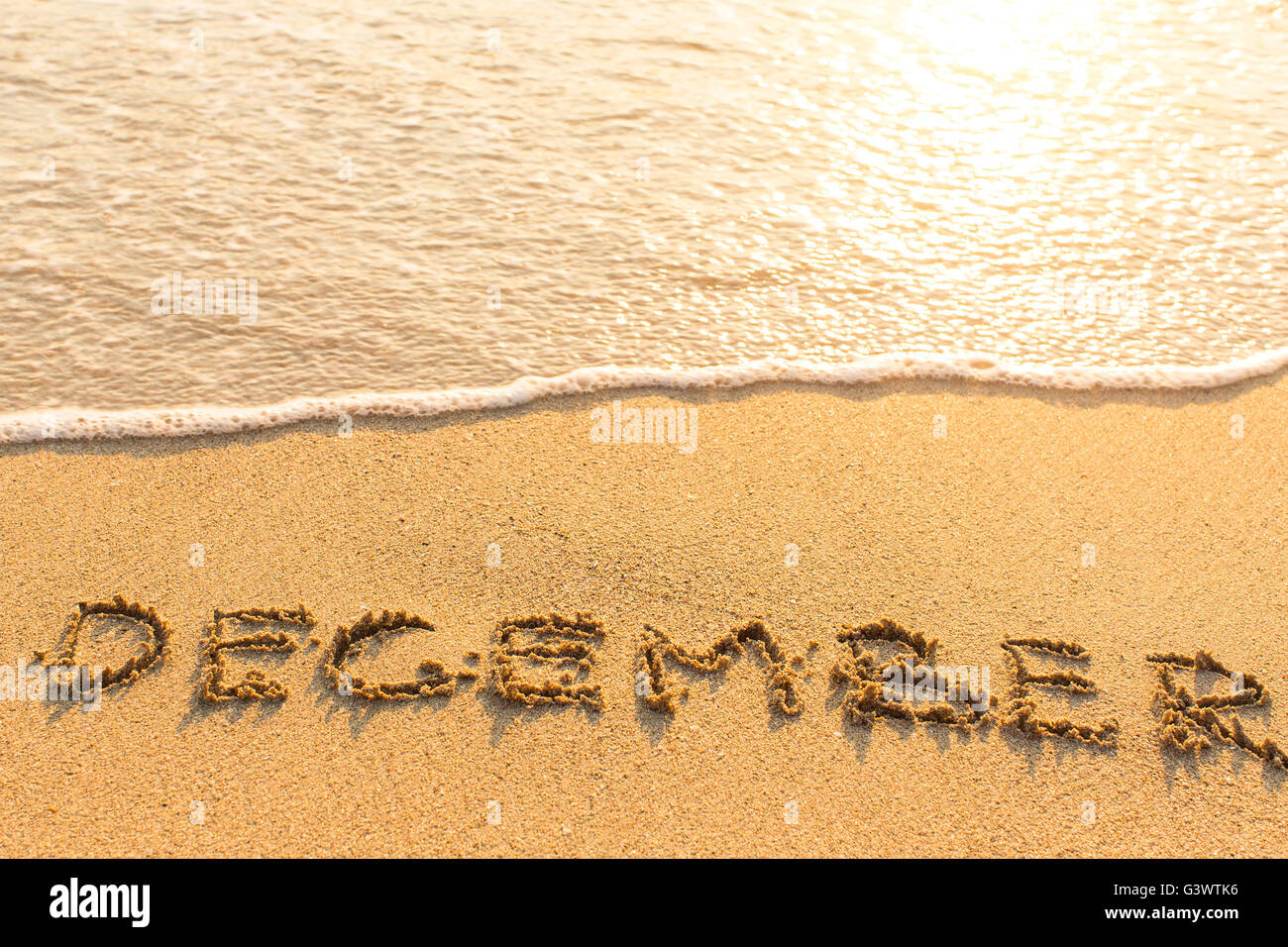 December - written on sandy beach with the soft wave Stock Photo - Alamy