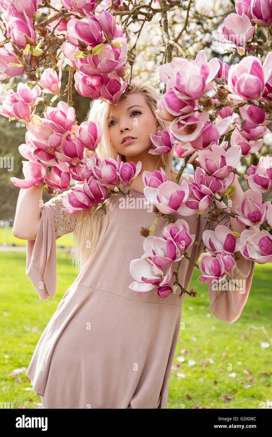 Portrait of a beautiful young woman posing under spring cherry blossoms ...