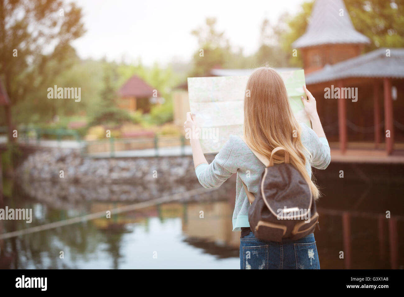 Back side of traveler girl searching right direction on map, orange ...