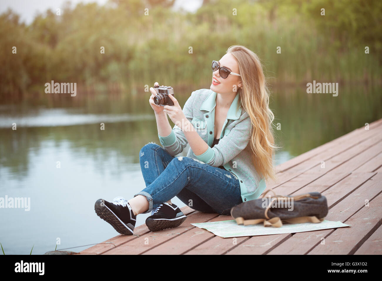 Pretty young woman traveling with photo camera and making pictures ...