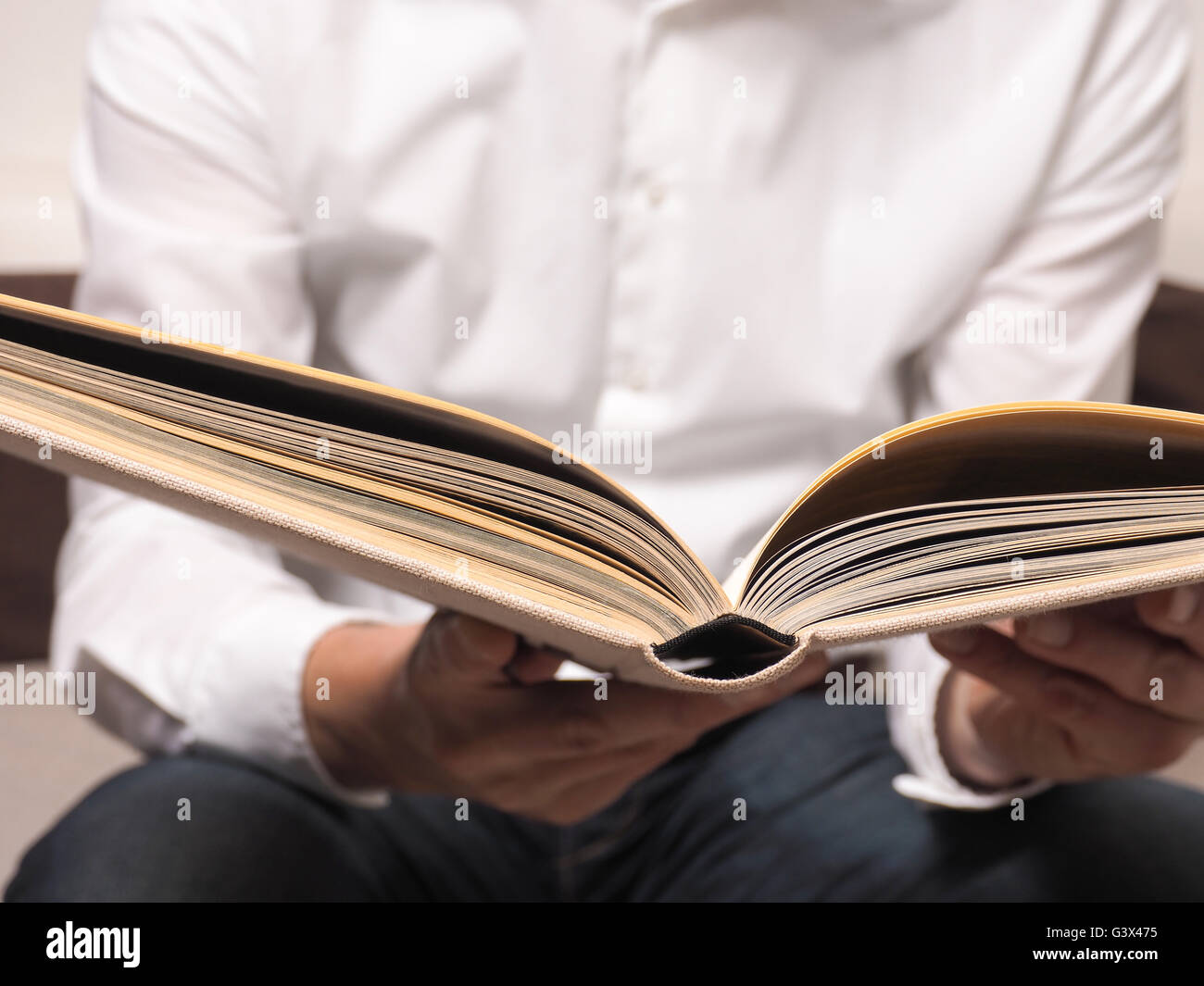 Handsome man reading an old book on a sofa Stock Photo - Alamy