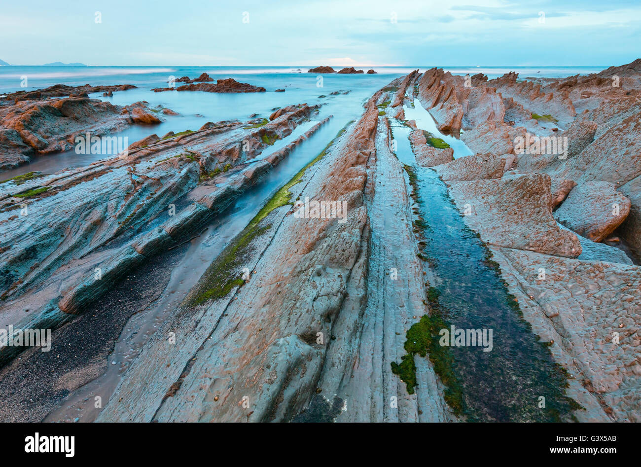 Twilight ocean coast with ribbed stratiform rock formations. (Atlantic ...
