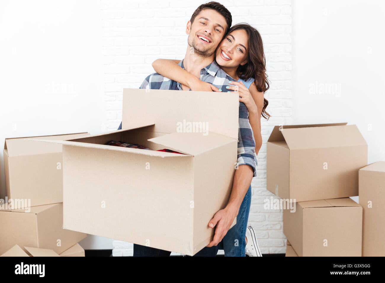 Smiling young married couple carrying cardboard boxes and hugging Stock ...