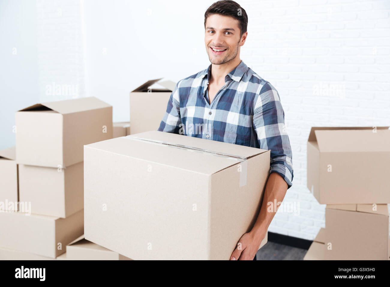 Smiling happy handsome man carrying carton boxes at new flat Stock ...