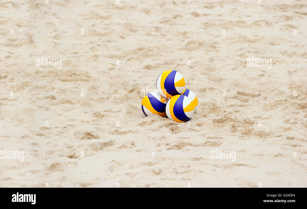 Volleyball beach is a stack of three volleyballs sitting in the sand ...