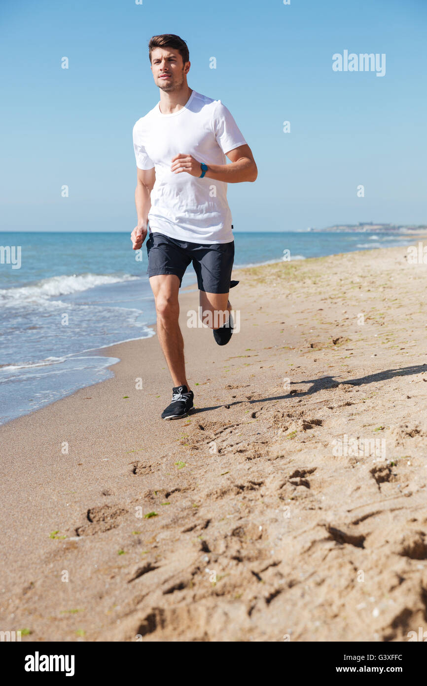 Attractive young sportsman jogging on the beach in the morning Stock ...