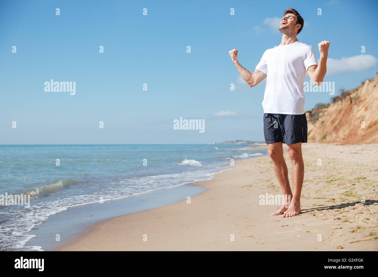 Happy excited young man with raised hands standing and celebrating ...