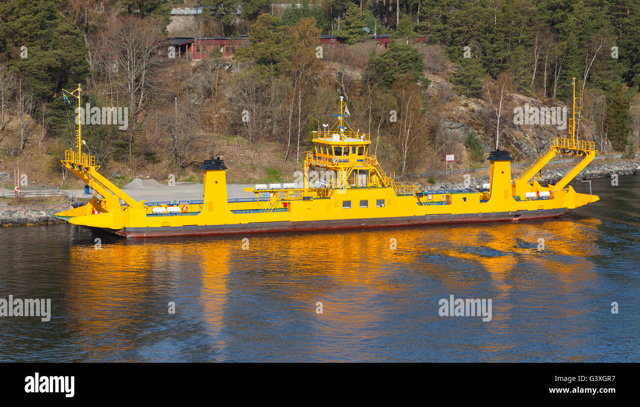 Yellow roro cargo ship goes near an island coast, Stockholm archipelago ...