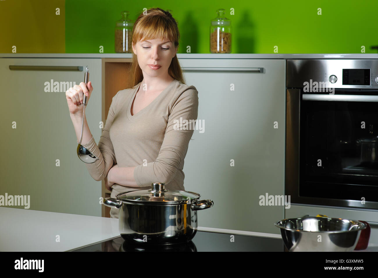 Girl on kitchen with a ladle. Smiling redhead woman with ladle cooking ...