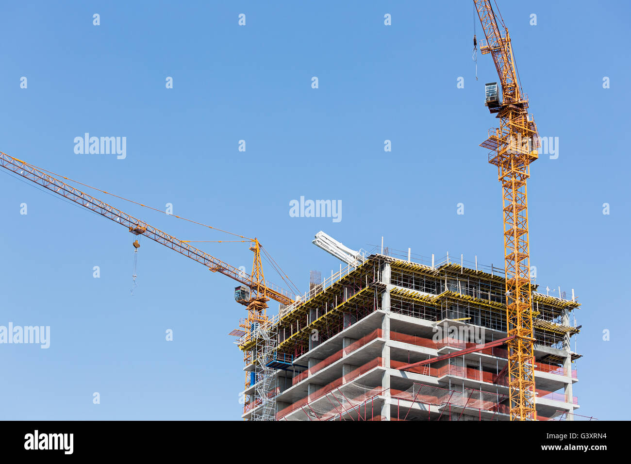 Condominium tower under construction with two yellow cranes Stock Photo ...