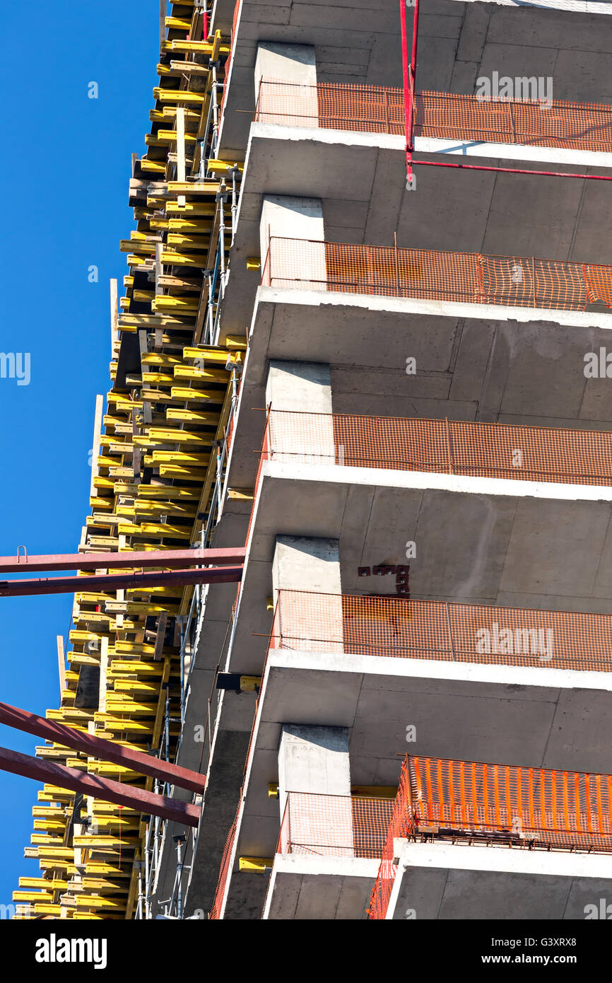 Concrete high-rise building under construction with protective mesh and ...