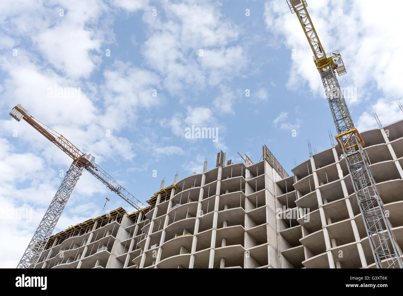 Unfinished building at construction site with tower cranes Stock Photo ...