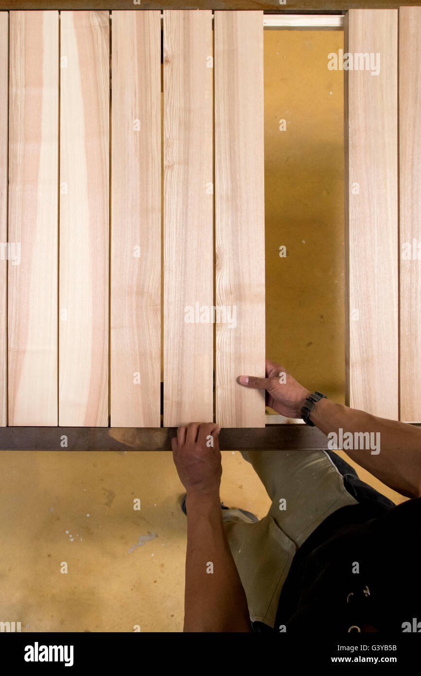 A carpenter assembling a table with wooden planks in a workshop Stock ...