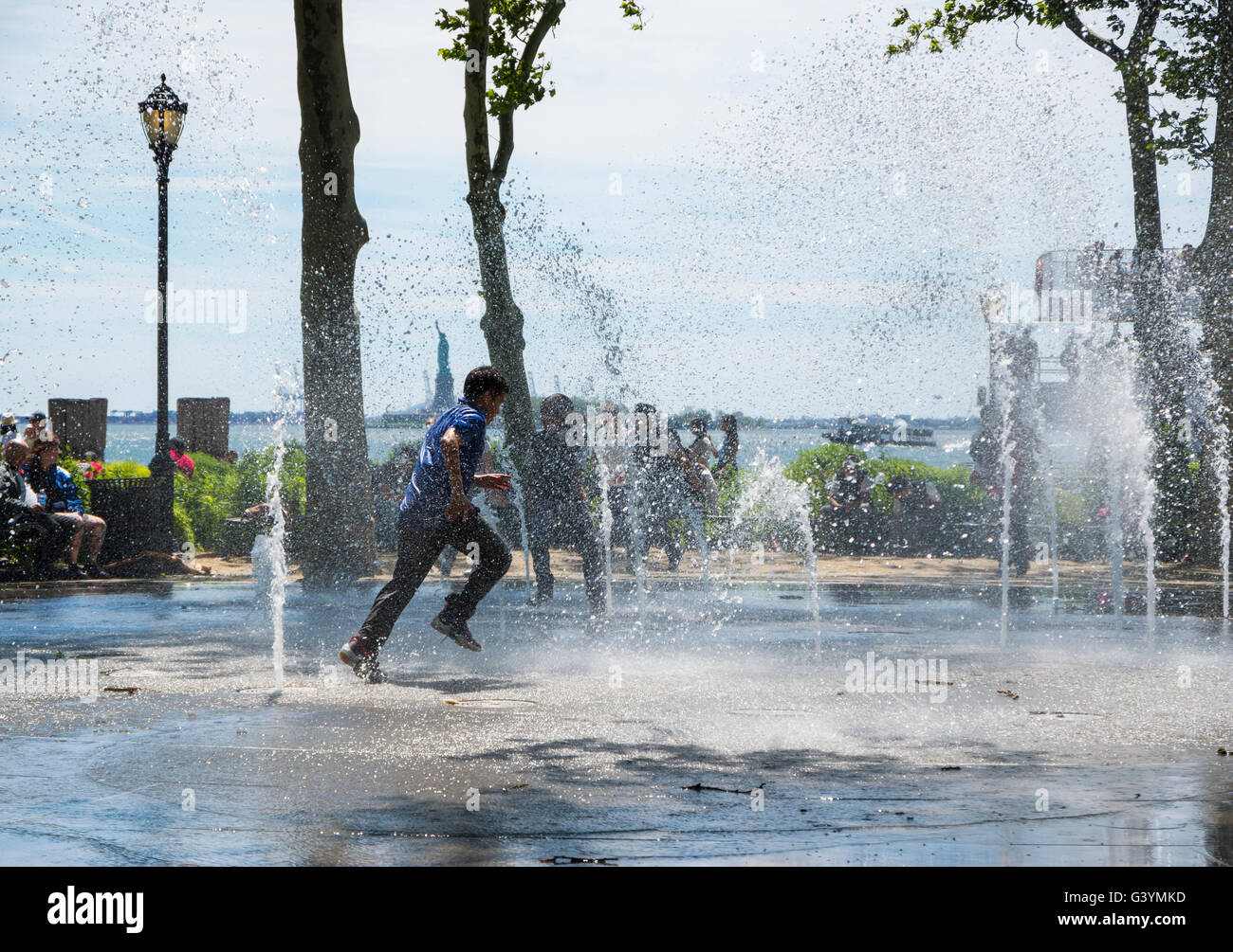 Teenage boys keeping cool in Summer by running through a public water ...