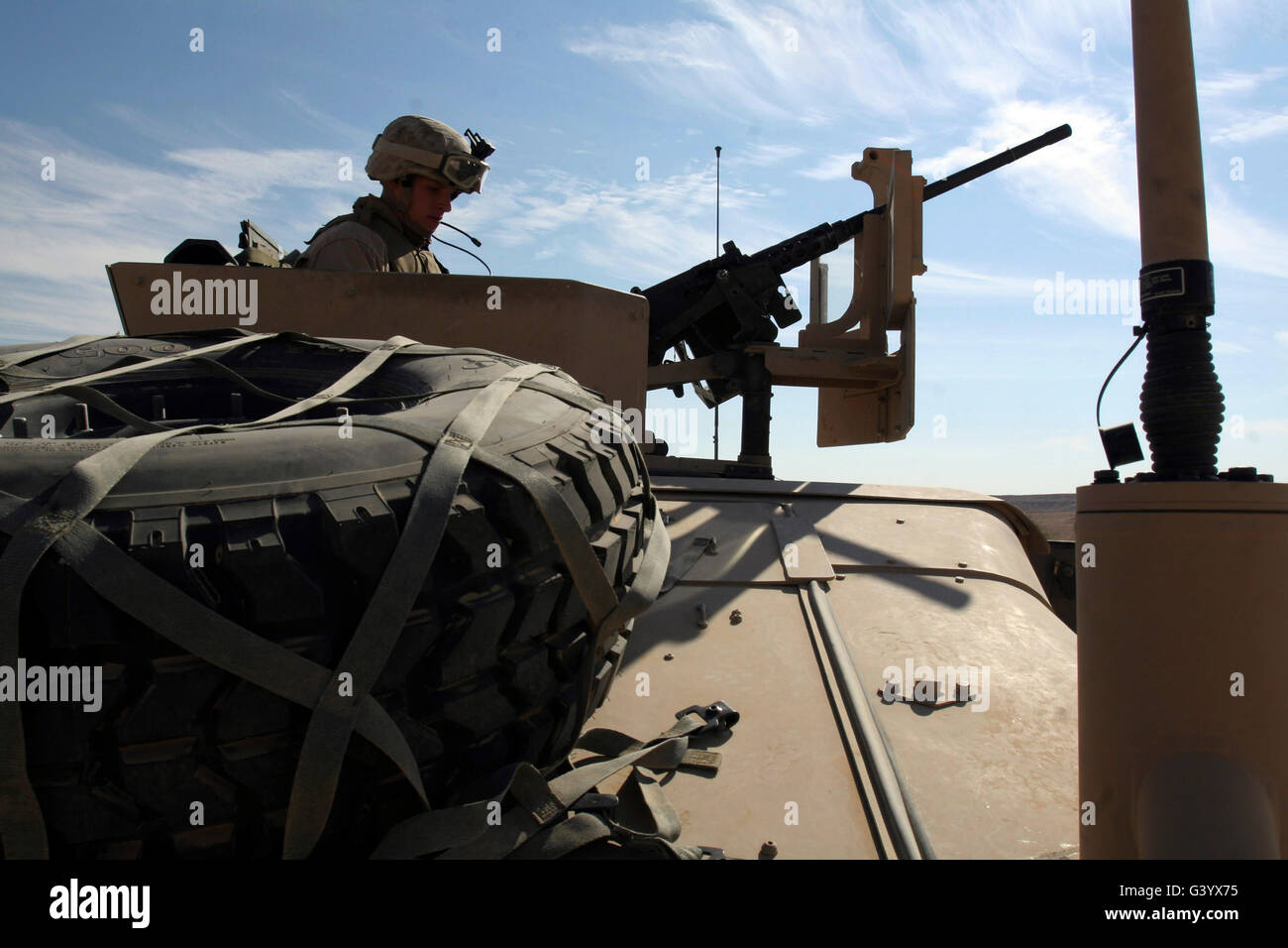 A marine glances down into his Humvee while maintaining perimeter ...