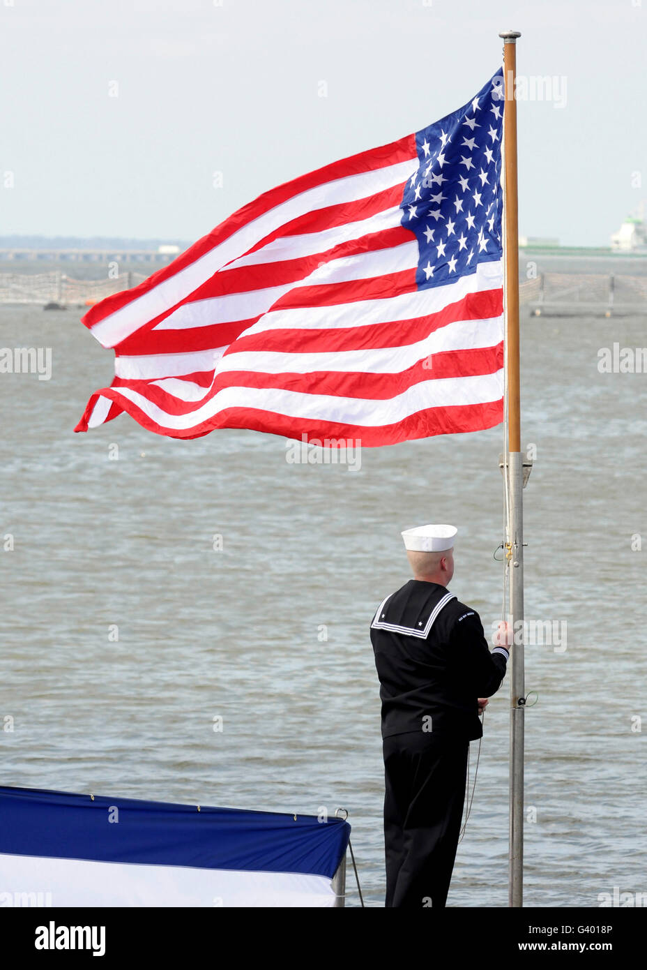 Sailor raises the National Ensign during a commissioning ceremony ...