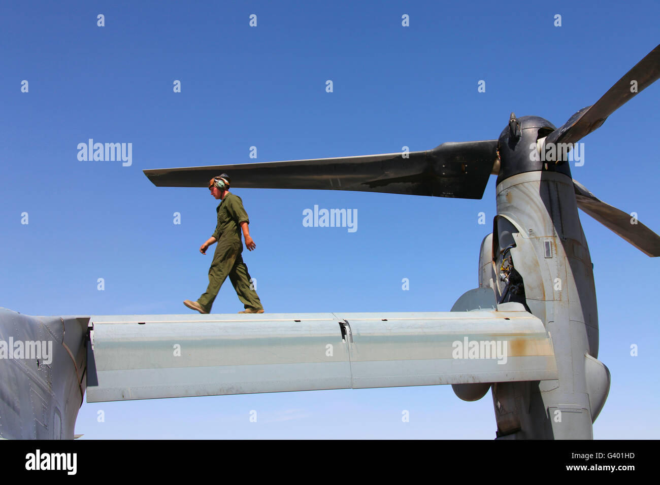 A flightline mechanic takes a look at the wings and rotors of an MV-22 ...