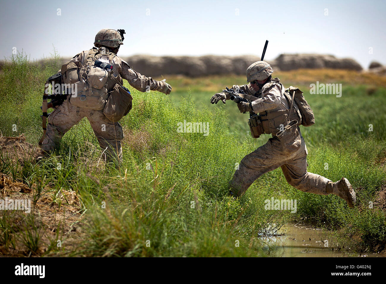 U.S. Navy Petty Officer extends a helping hand to a Marine jumping a ...