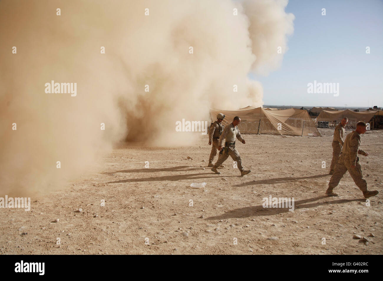 U.S. Marines walk away from a dust cloud at a military base in ...