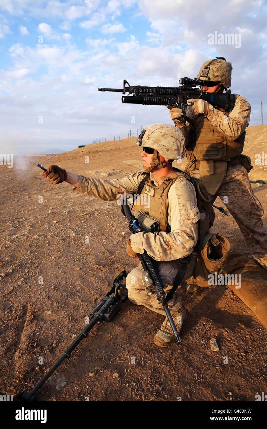 A Marine fires a M203 grenade launcher while fellow Marine fires a pin ...