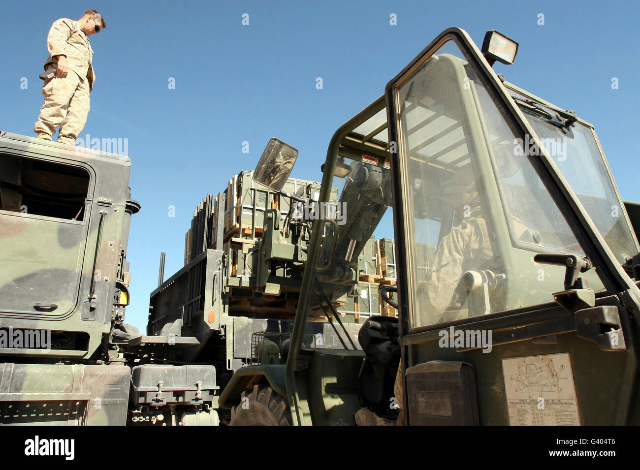 A Marine manning a front-loading forklift maneuvers a pallet of mortar ...