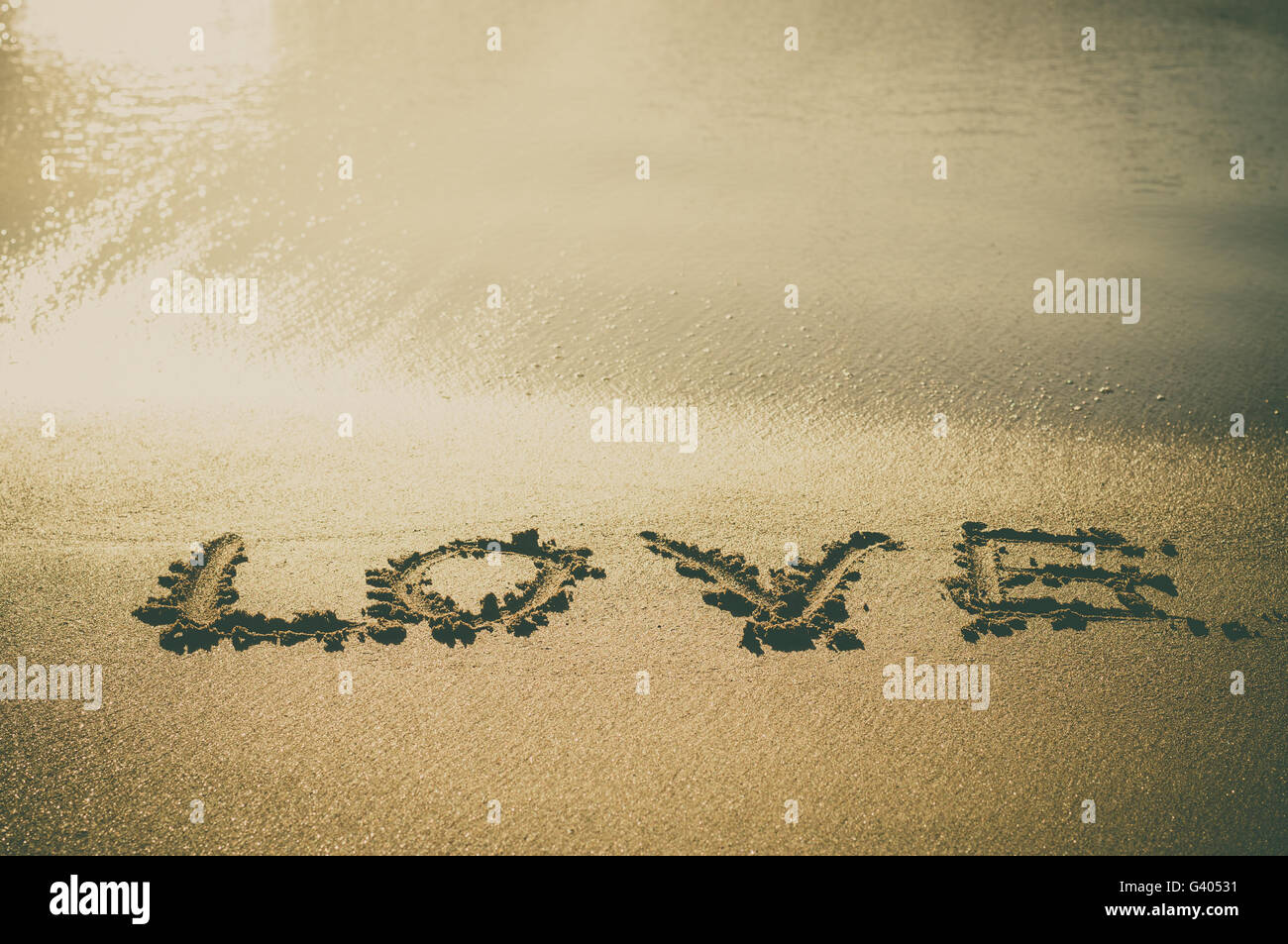 Love text wrote on beach sand near sea water, vintage instagram toned ...