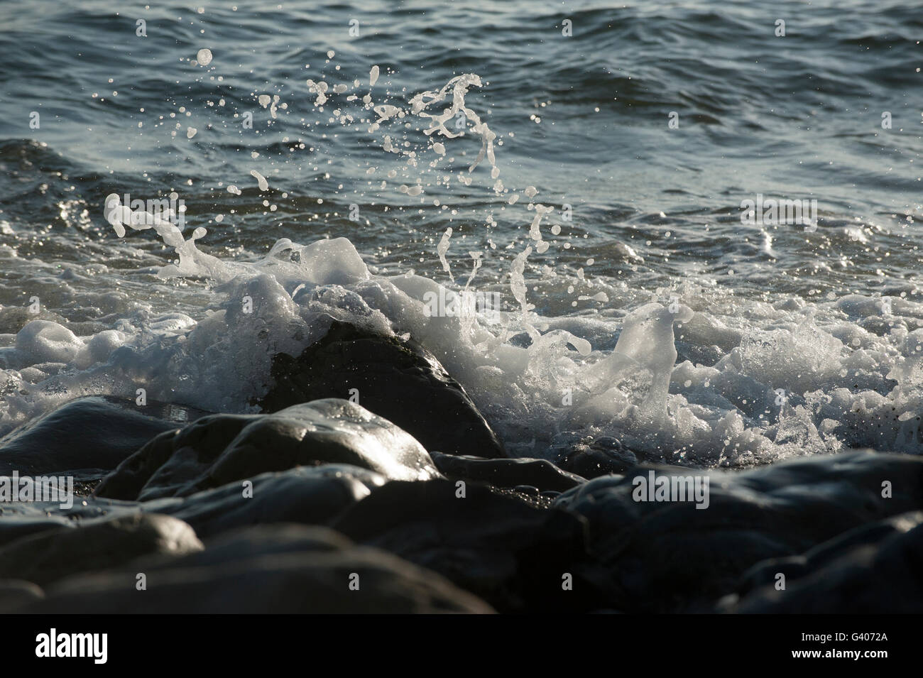 Sea water splashes on rocks as the tide come in on a Welsh beach Stock ...