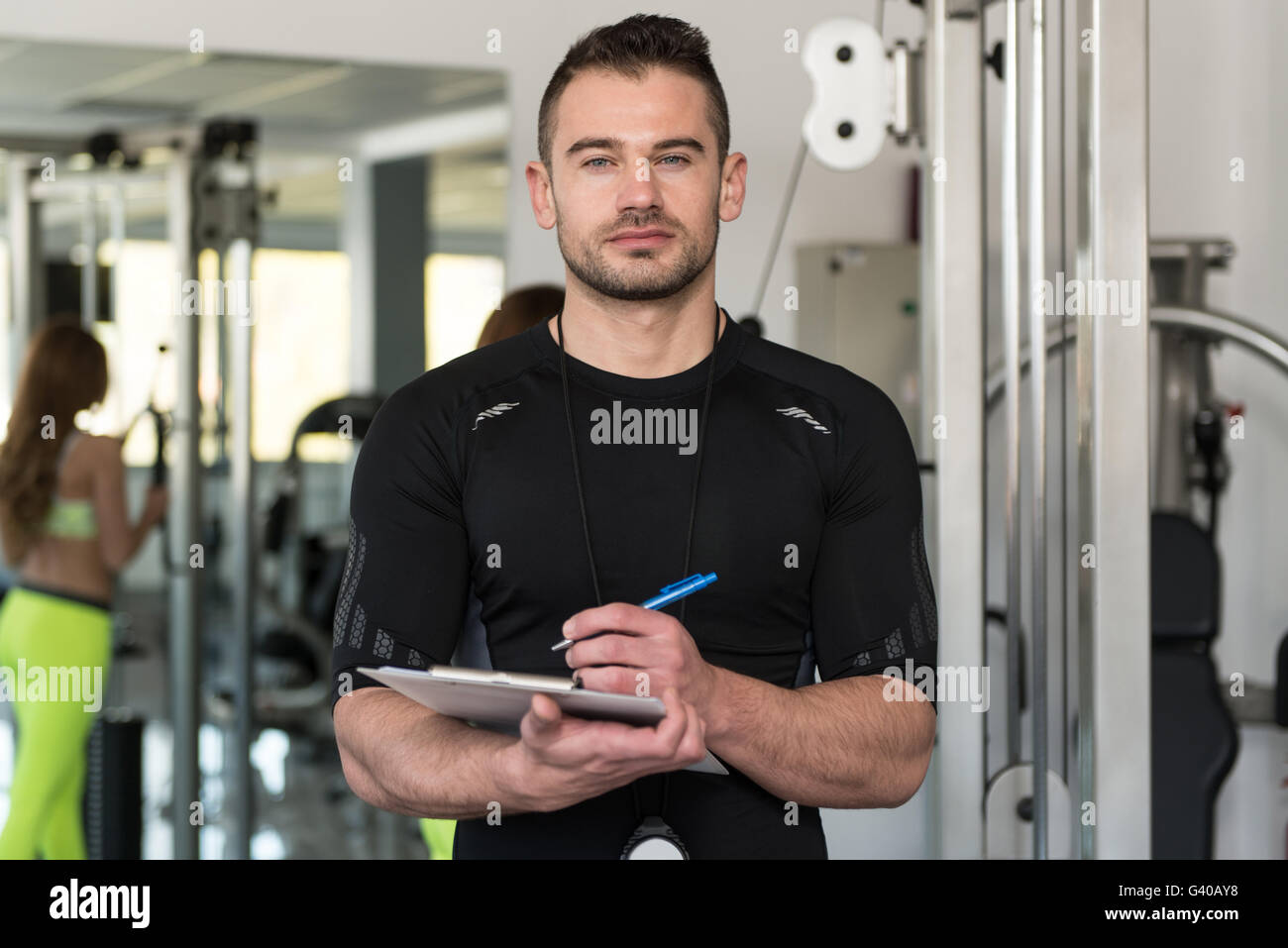 Personal Trainer With Clipboard Monitors People While They Exercise In ...