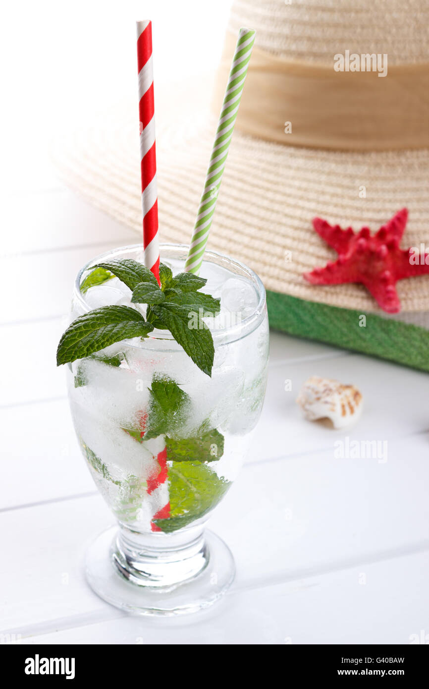 Refreshing summer drink, fizzy water with ice and mint with beach ...