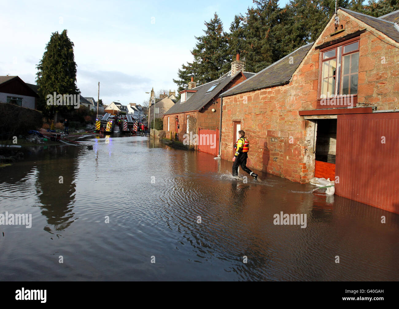 A fireman walks through flood waters in Back Street, Bridge of Earn ...