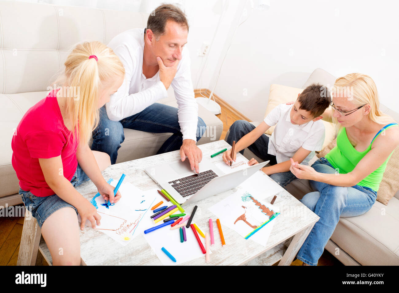 Kids drawing with happy parents on the couch Stock Photo - Alamy