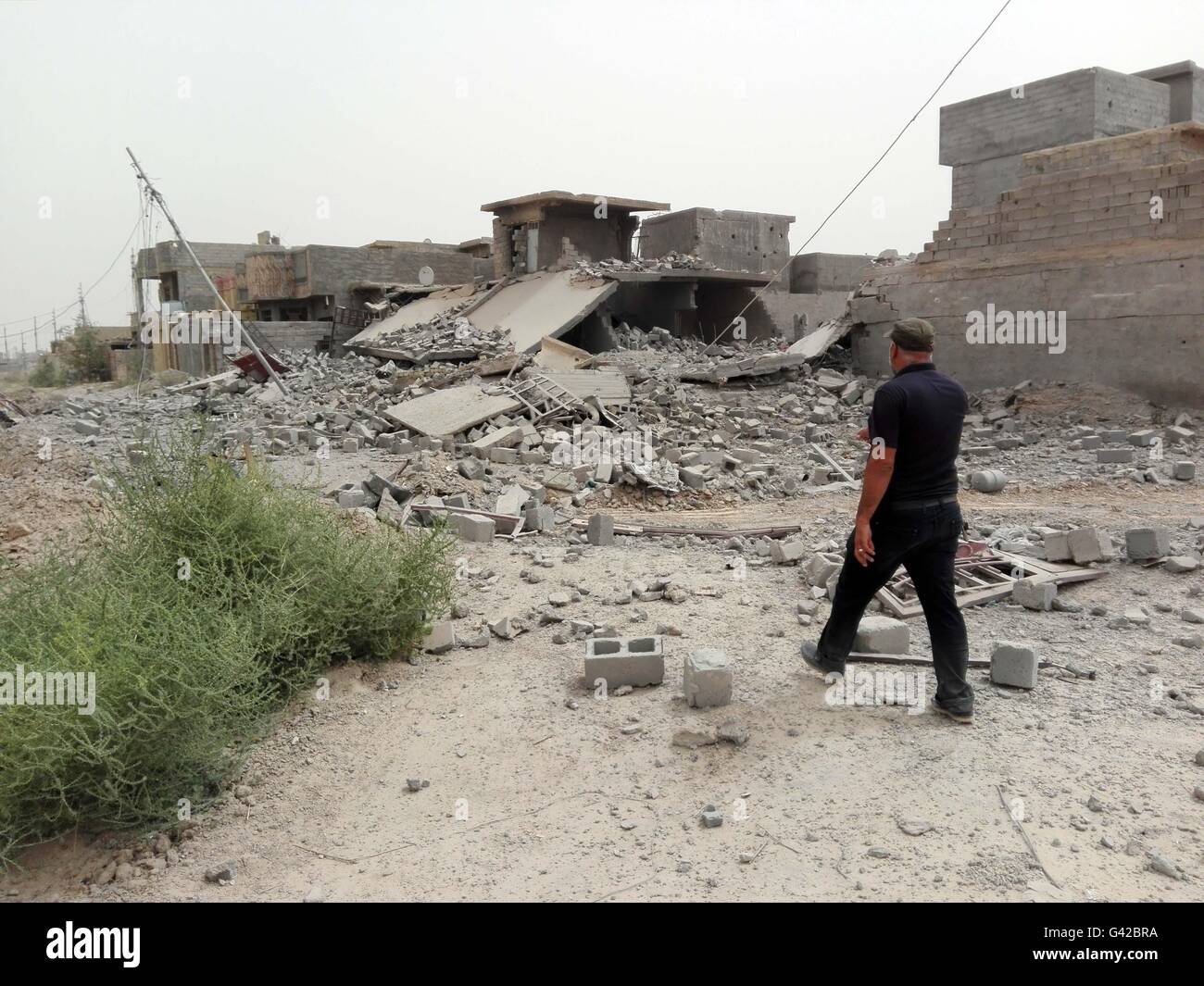 Fallujah, Iraq. 17th June, 2016. An Iraqi soldier walks near destroyed ...