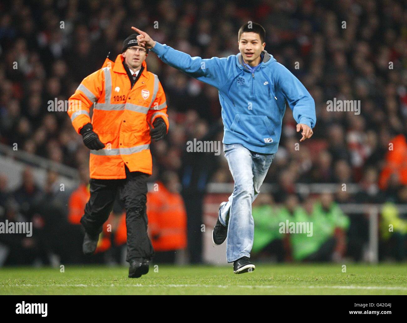 A pitch invader gives an arsenal steward the slip hi-res stock ...